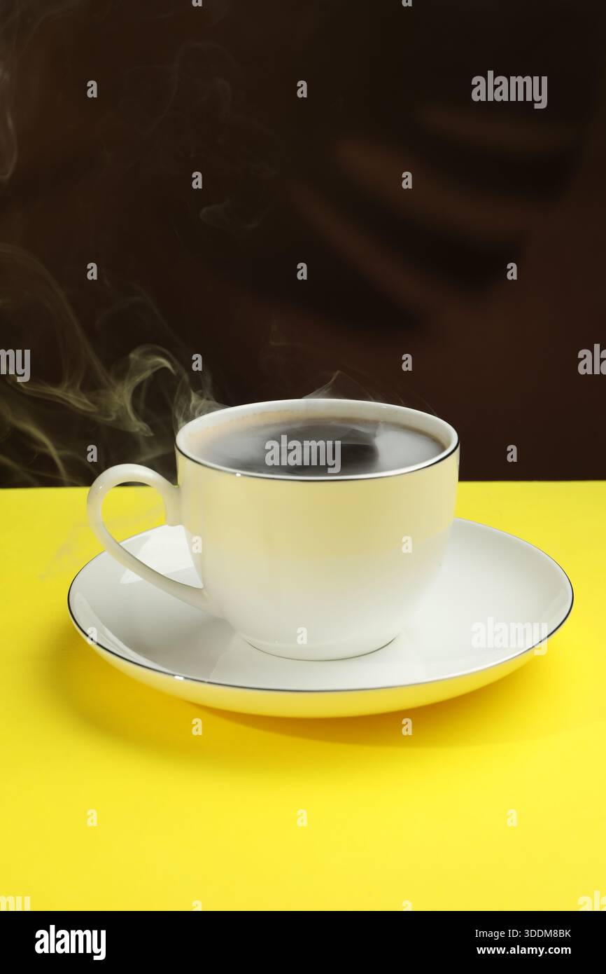 Aromatic coffee in cup on yellow table against dark background Stock ...