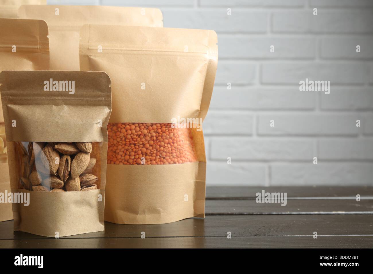 Stand-up pouches with different products on wooden table against white ...