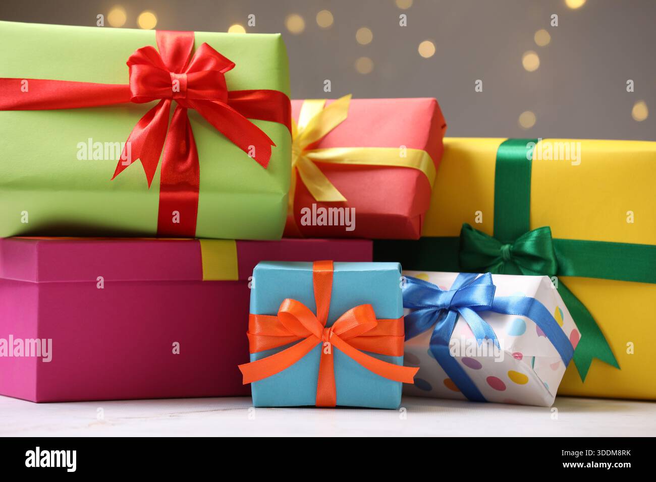Beautiful gift boxes on white table against grey background with bokeh ...