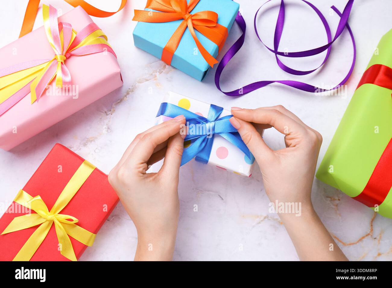 Woman with beautiful wrapped gifts on white marble background, top view ...