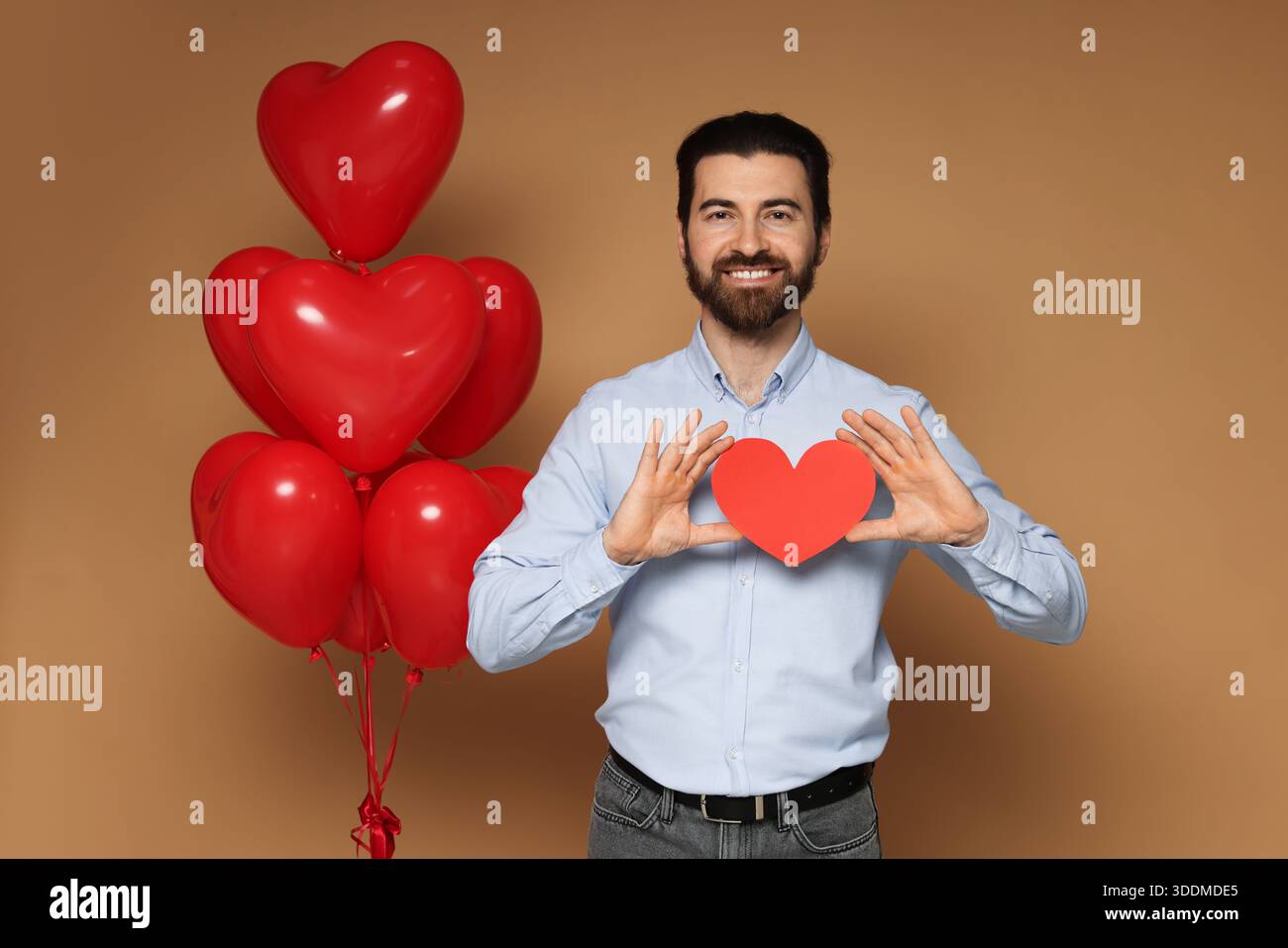 St. Valentine's Day. Man with paper heart and balloons on beige ...