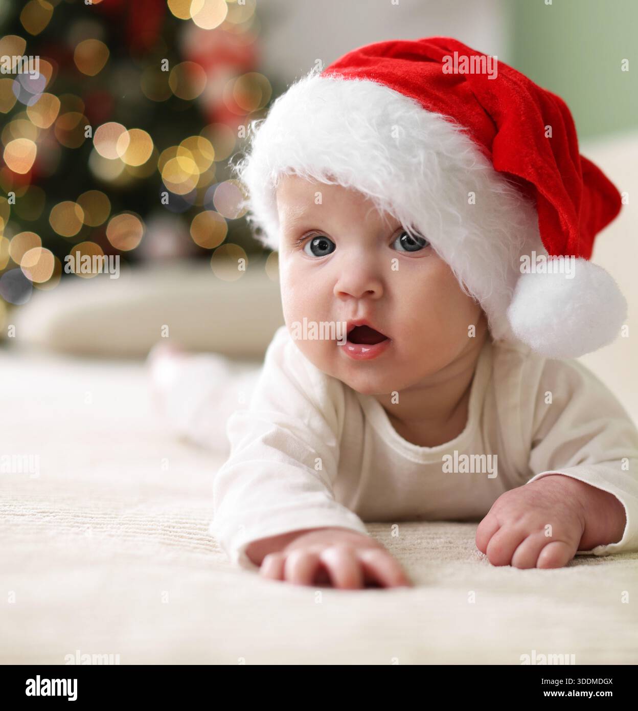 Cute little baby in Santa hat on sofa against Christmas lights, bokeh ...