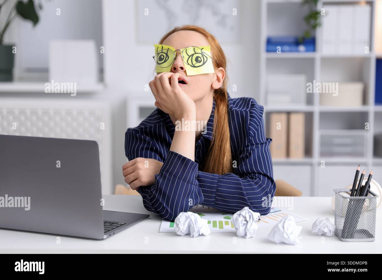 Woman with fake eyes drawn on sticky notes snoozing at workplace in ...