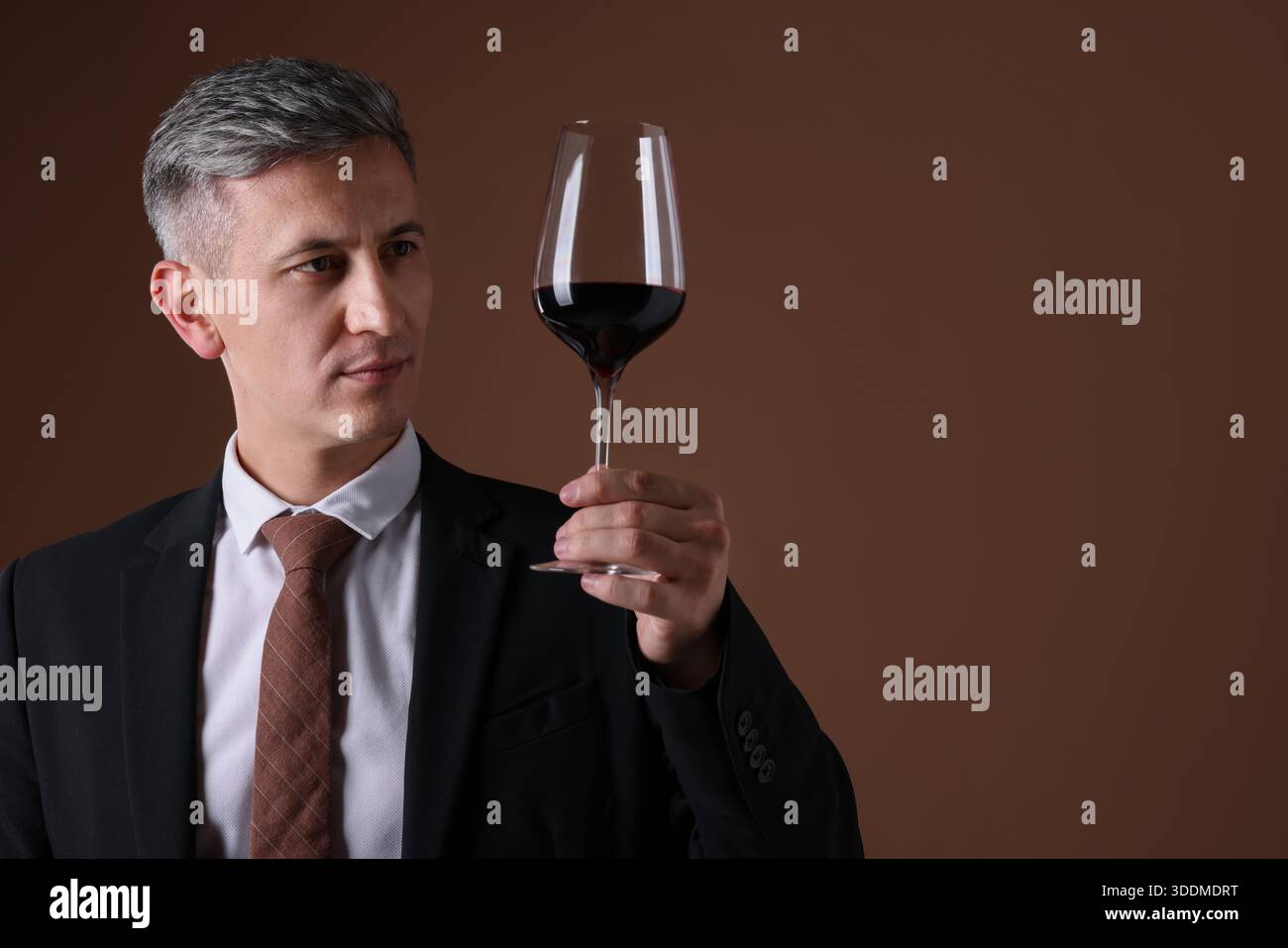 Professional sommelier with glass of red wine on brown background ...