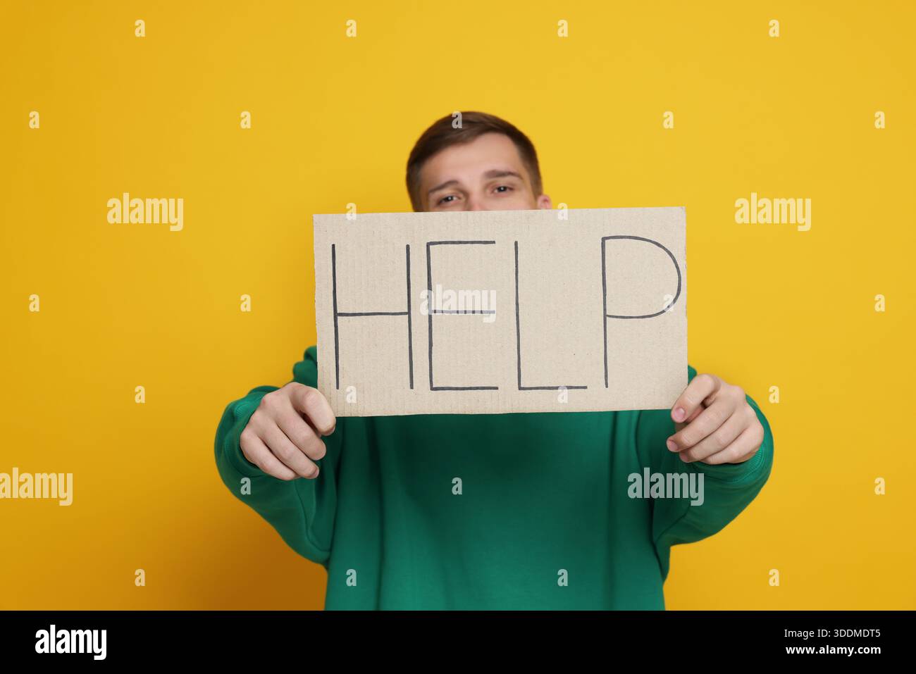 Man holding sign with word Help on yellow background Stock Photo - Alamy