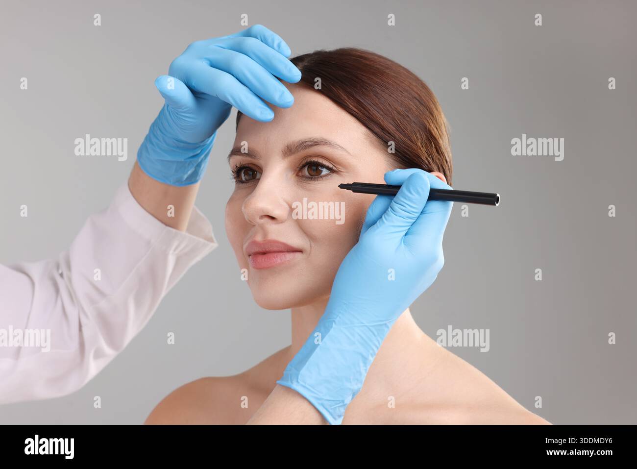 Doctor drawing marks on patient's face for plastic surgery operation ...
