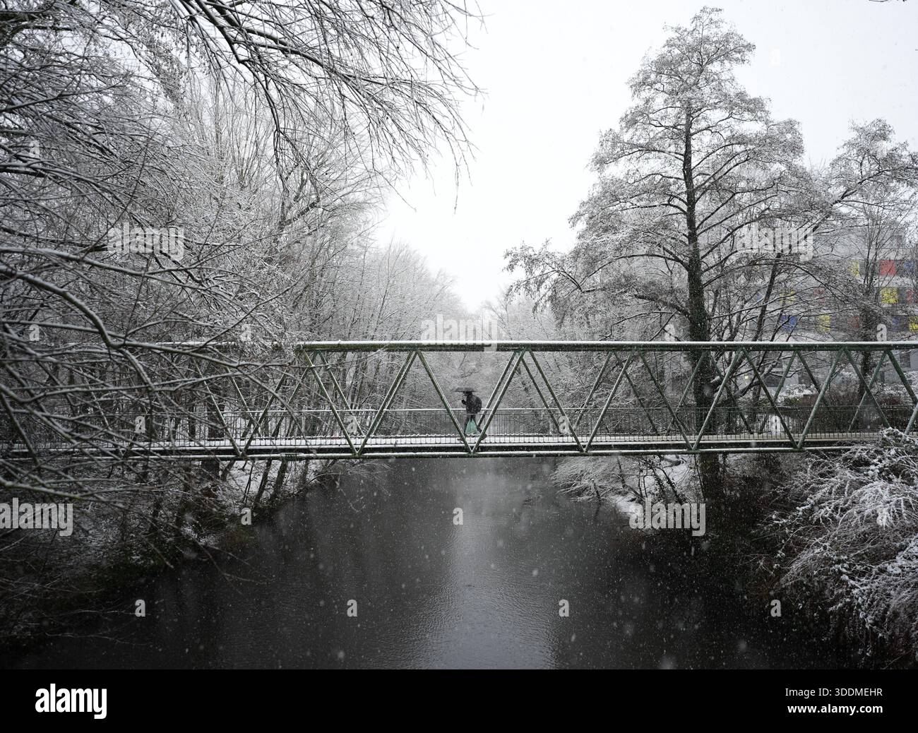 02 January 2026, Hamburg: A passer-by crosses a canal bridge in wintry ...