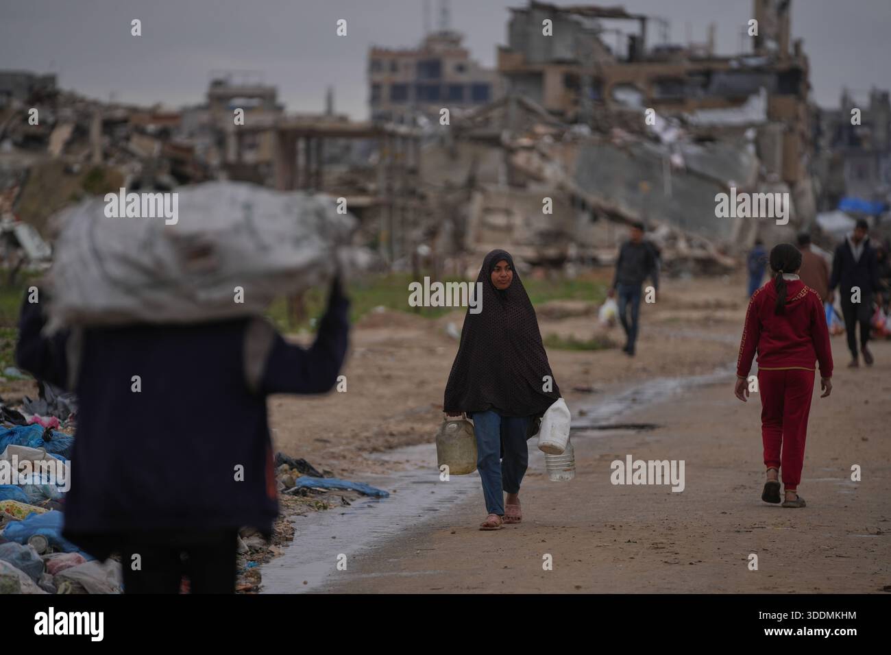 A Palestinian woman carries a container of water in Nuseirat, central ...