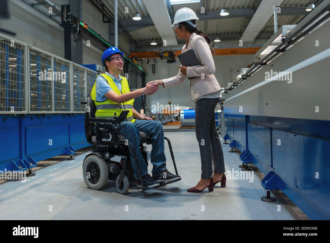 Female production supervisor talking to employee with disability in ...