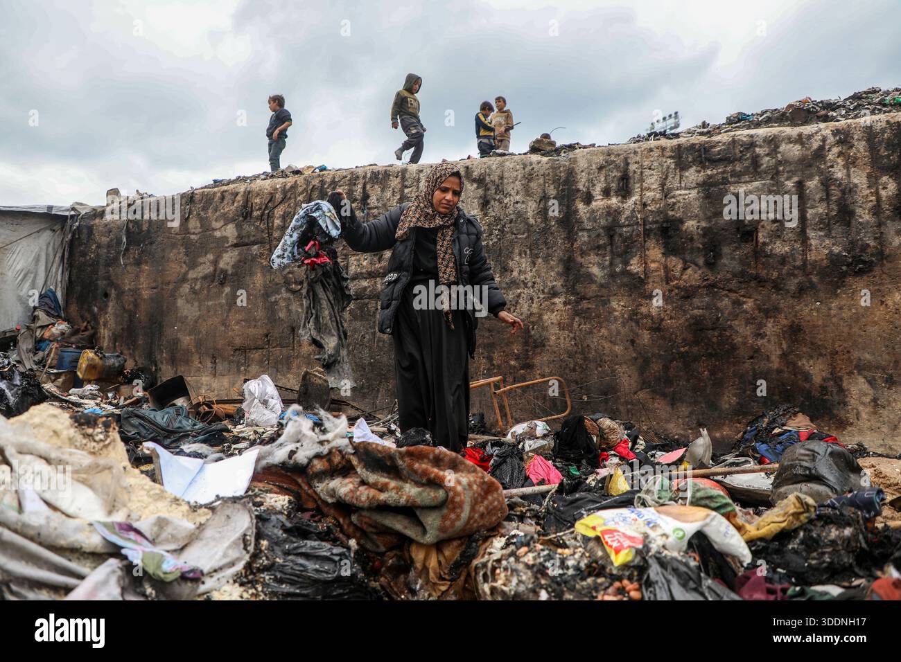 Gaza. 2nd Jan, 2026. A displaced Palestinian woman inspects the damage to her temporary tent ...