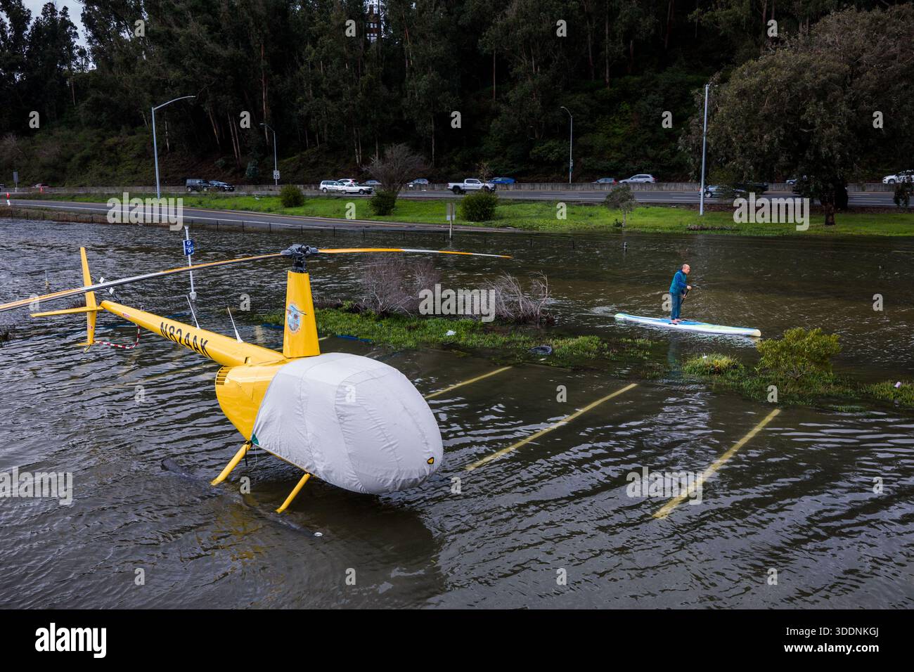 A person paddle boards along a flooded street caused by the king tides ...