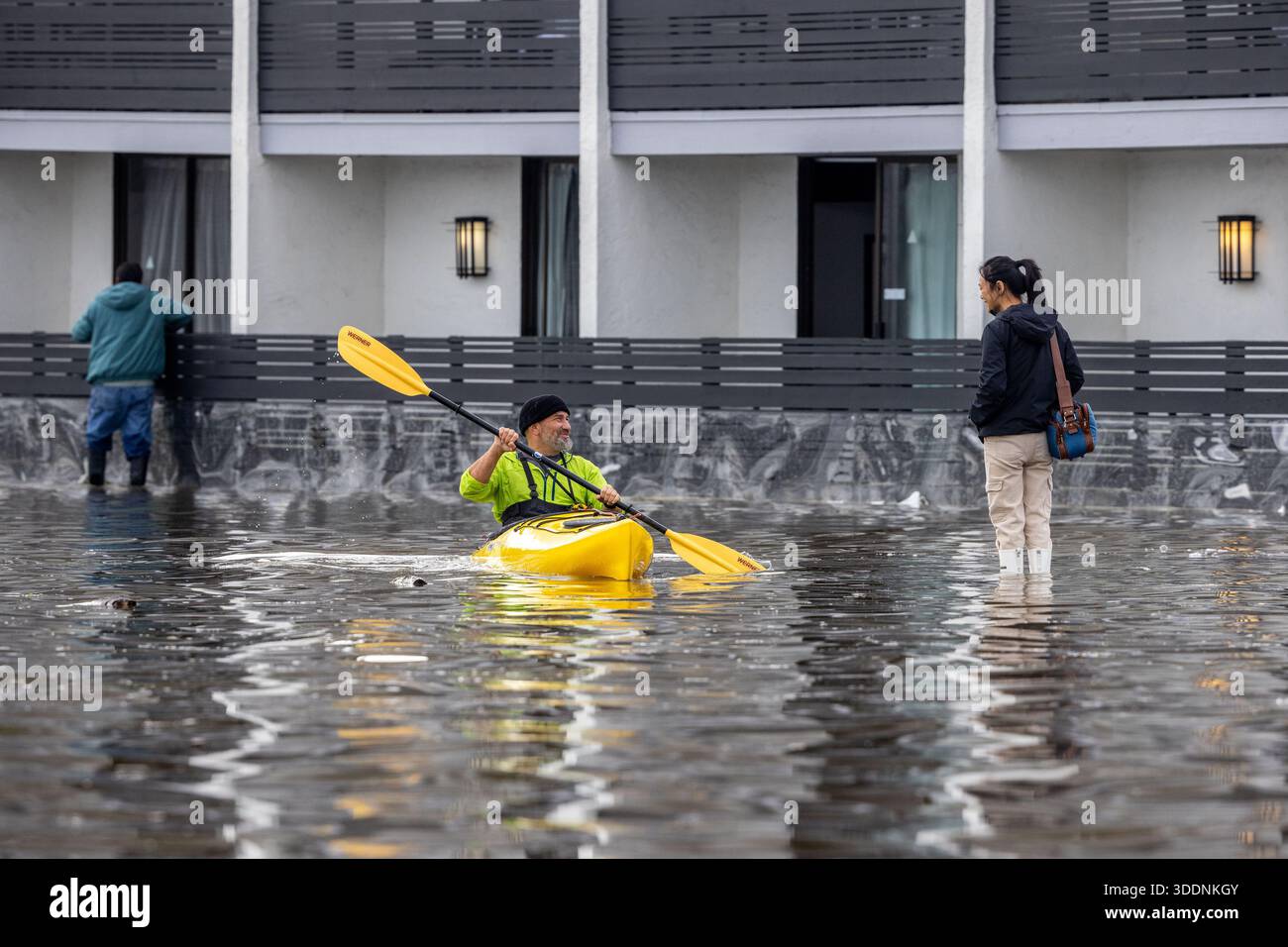 People gather outside the Holiday Inn Express, that was flooded by the ...