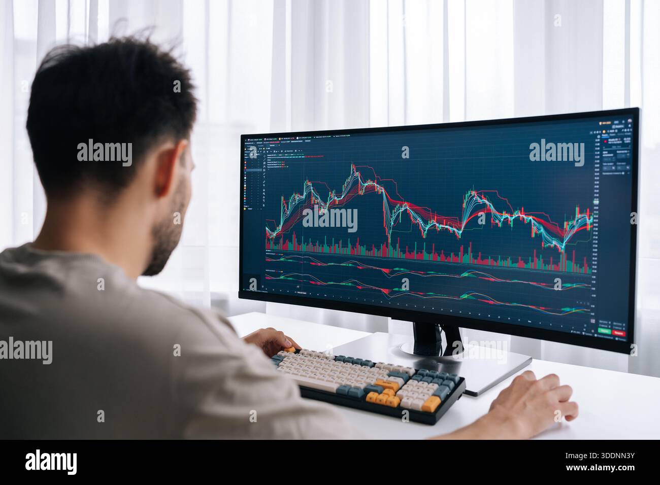 Rear view of young focused man monitoring stock market activity on ...