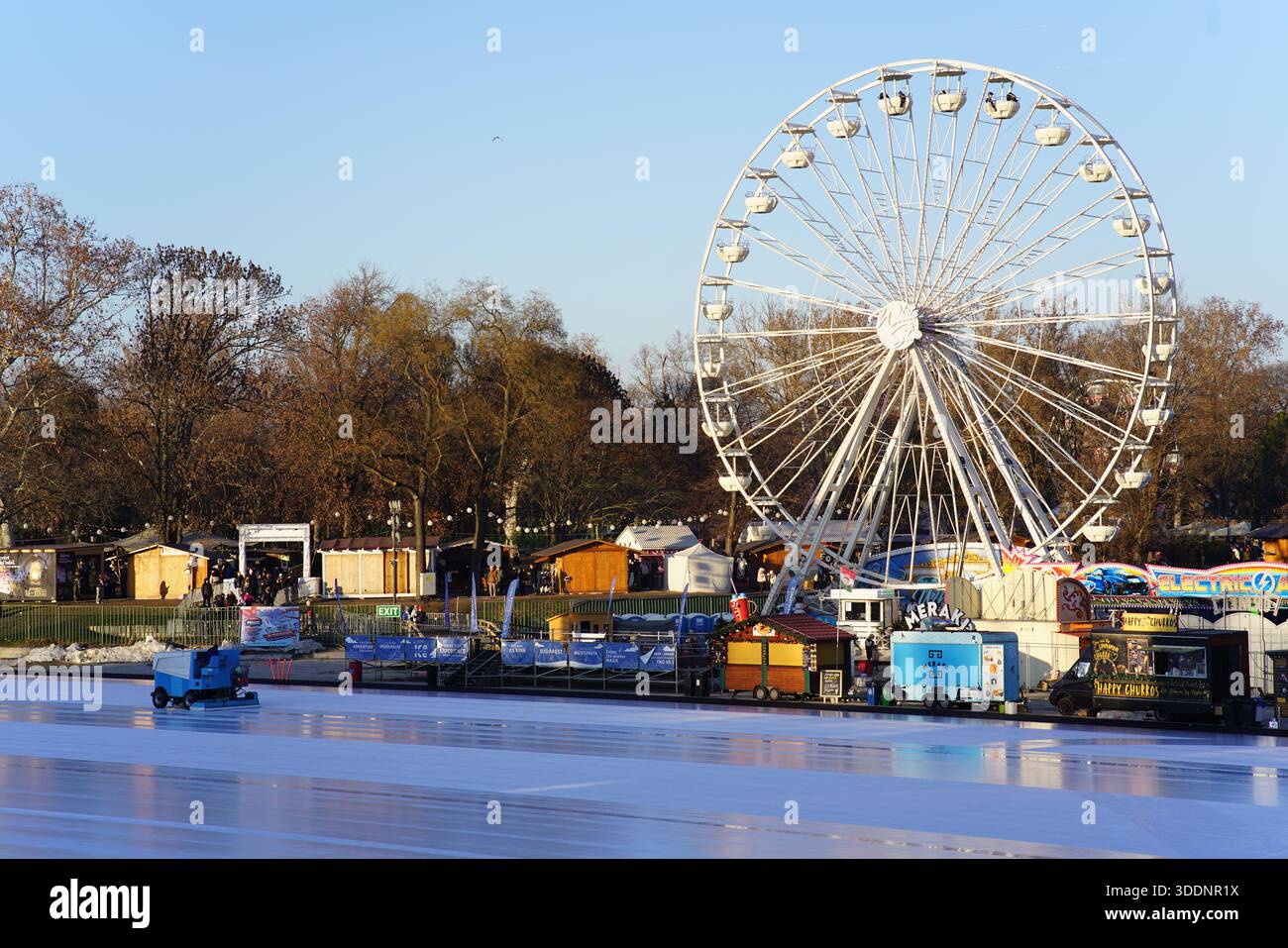 Ferris wheel and fairground rides overlooking an outdoor ice rink being ...