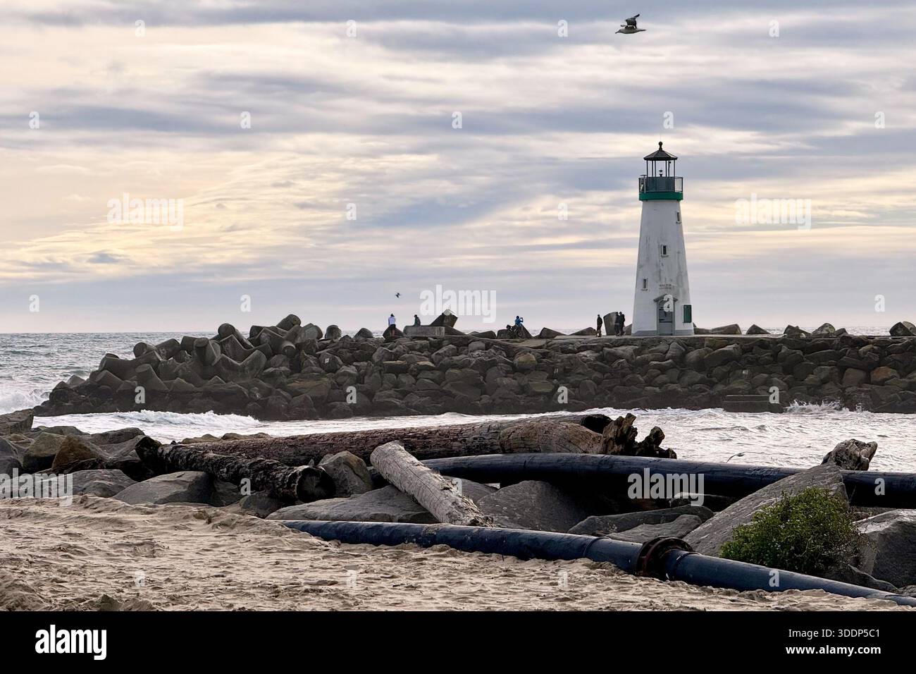 People walk on the jetty by the lighthouse at Twin Lakes State Park on ...