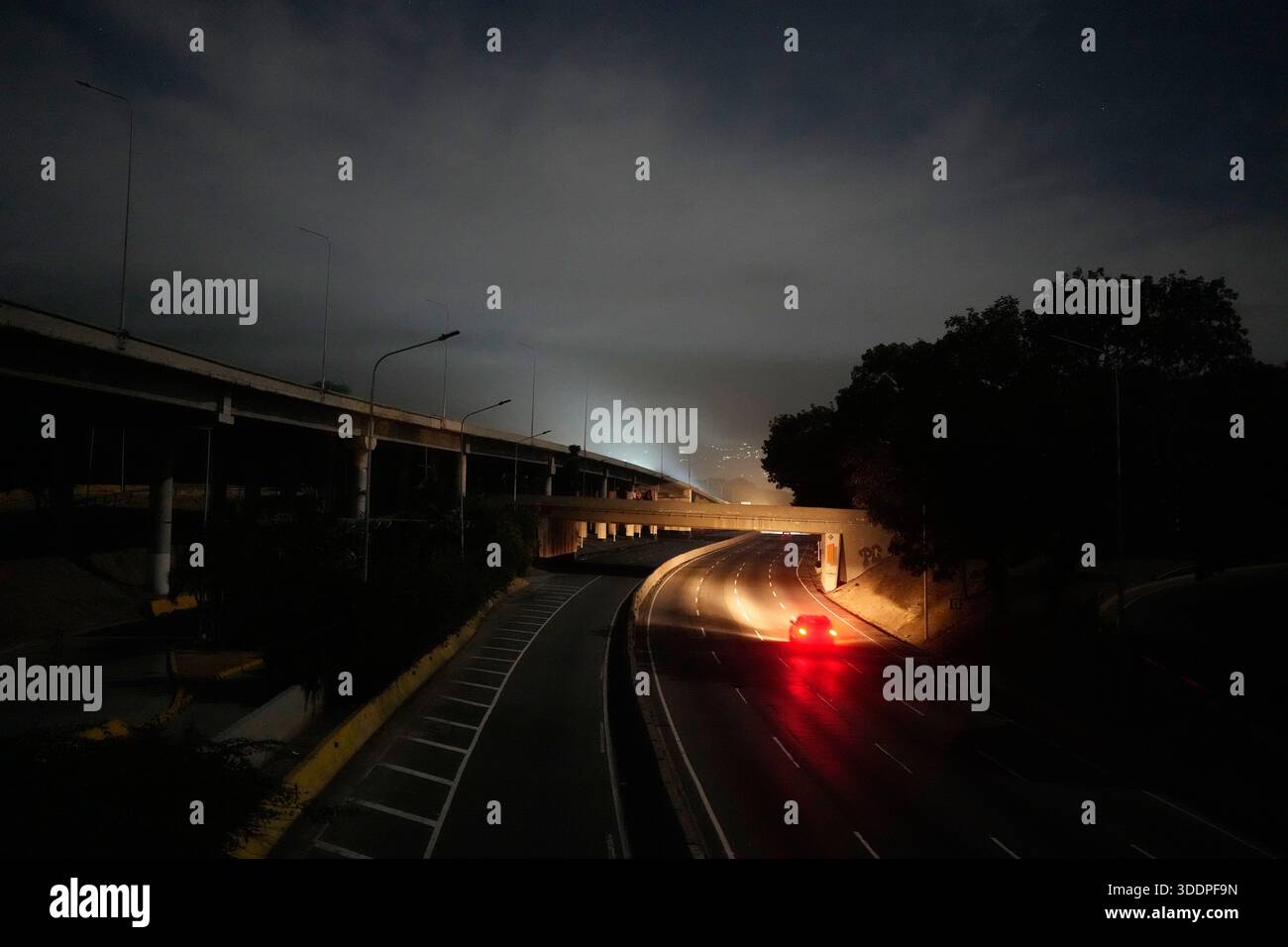 A vehicle drives along a darkened highway next to Fort Tiuna, the main ...