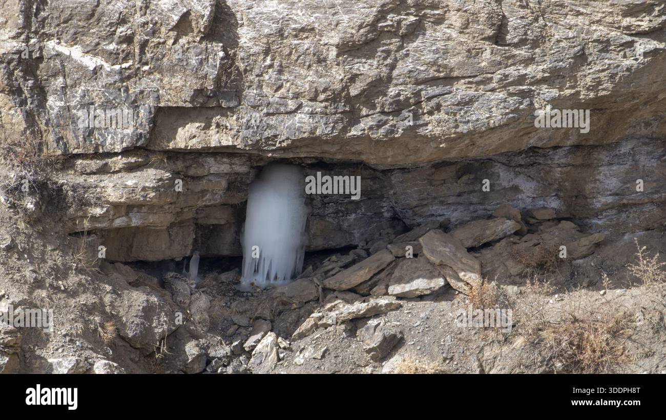 A cave with ice formations hanging within rocky terrain, displaying ...
