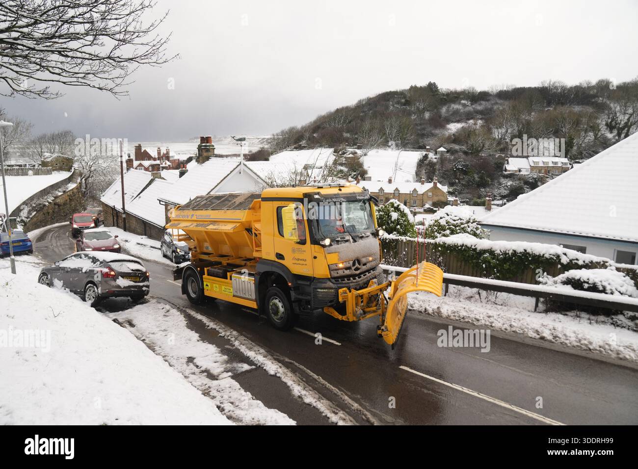 A gritter on road in snow covered Sandsend near Whitby, Yorkshire ...