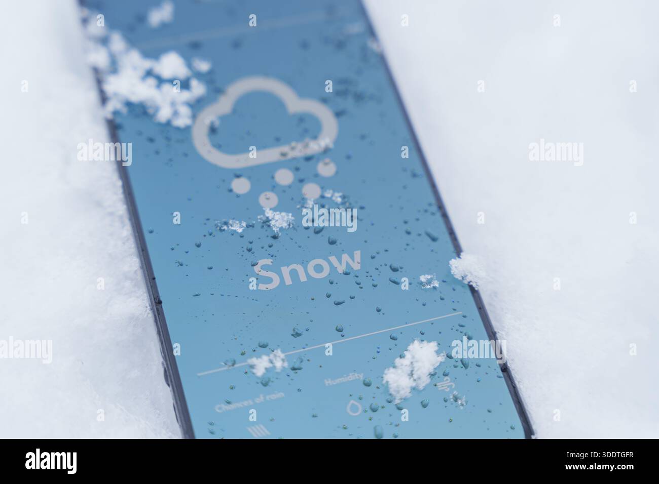 Smartphone lying in snow outdoors with weather app screen showing snow ...