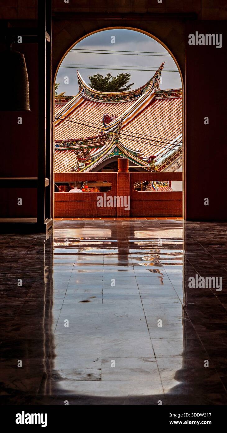 View of traditional Asian temple roof through an arched doorway, with ...