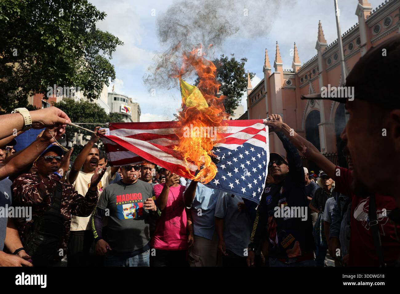 03 January 2026, Venezuela, Caracas: Venezuelans burn a US flag after ...
