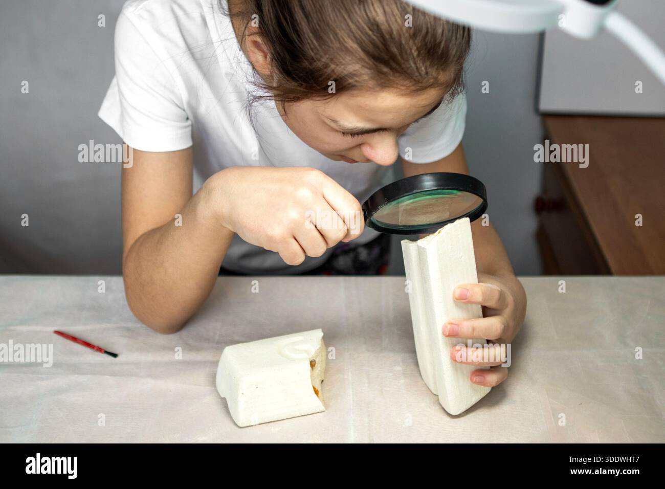 Child examines foam block with magnifying glass during a science ...