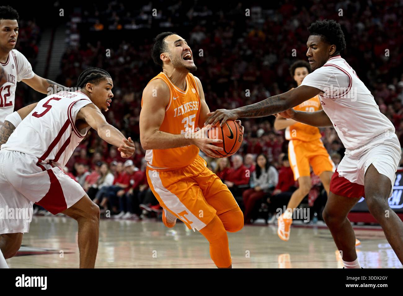 Tennessee guard Ethan Burg (35) tries to drive past Arkansas defenders ...