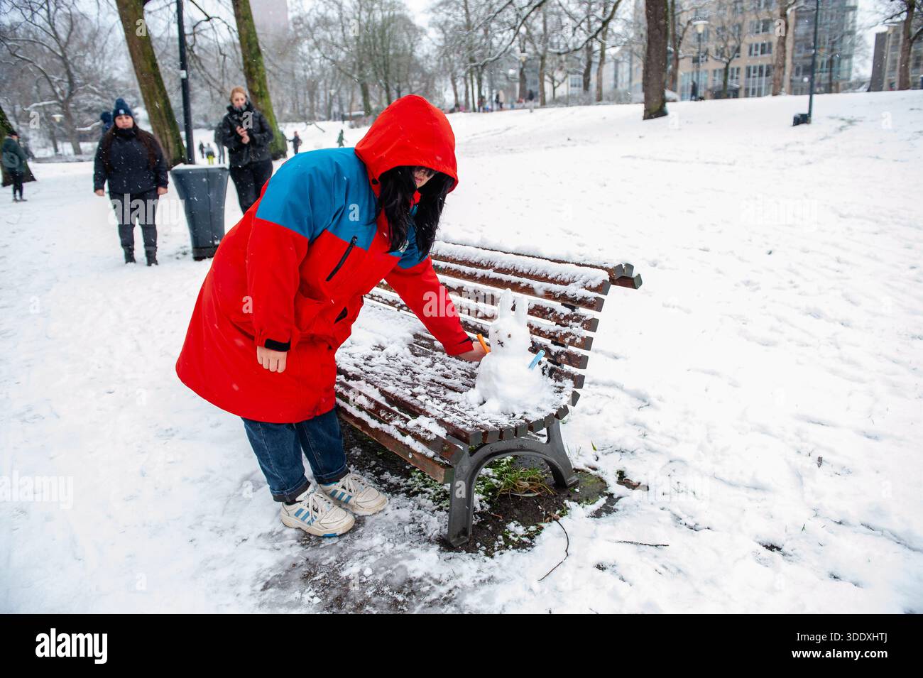 A woman is making a funny snowman. Storm Anna brought strong winds and ...