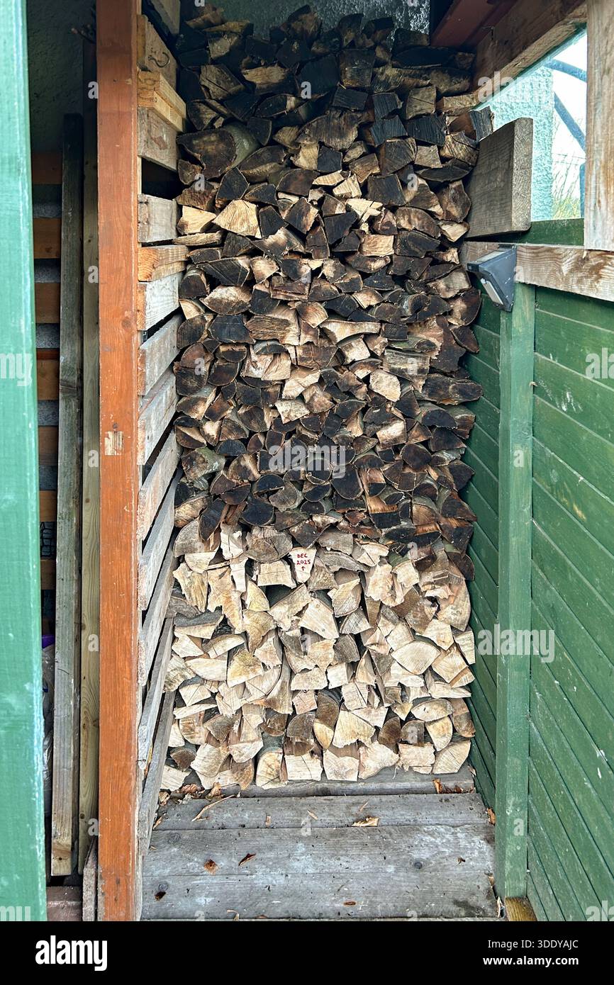 Layers of split & dried logs stacked in a home-made log store, ready ...