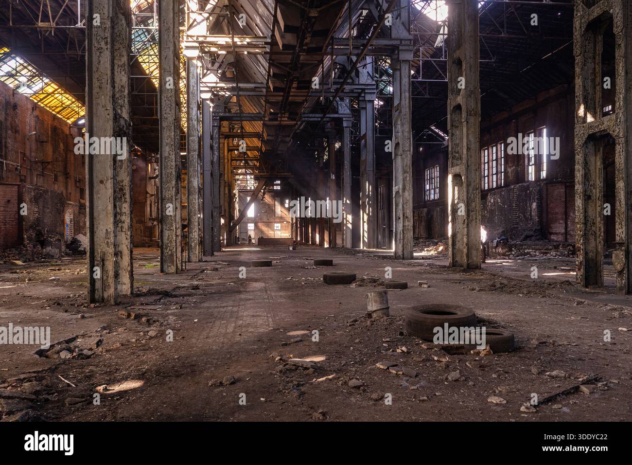 Wide view of abandoned industrial hall with concrete columns debris and ...