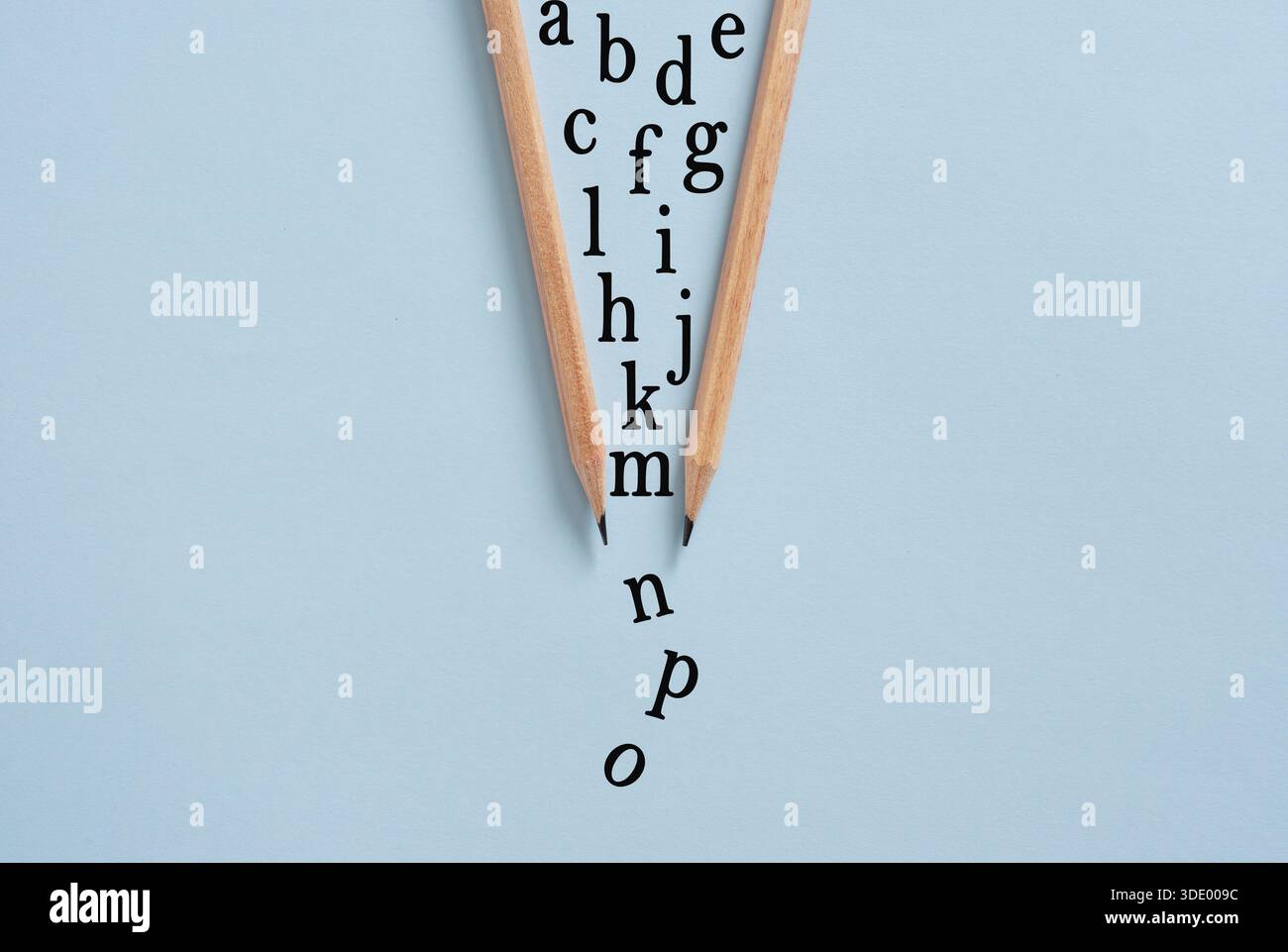 Pencils writing alphabet letters on a light blue background ...