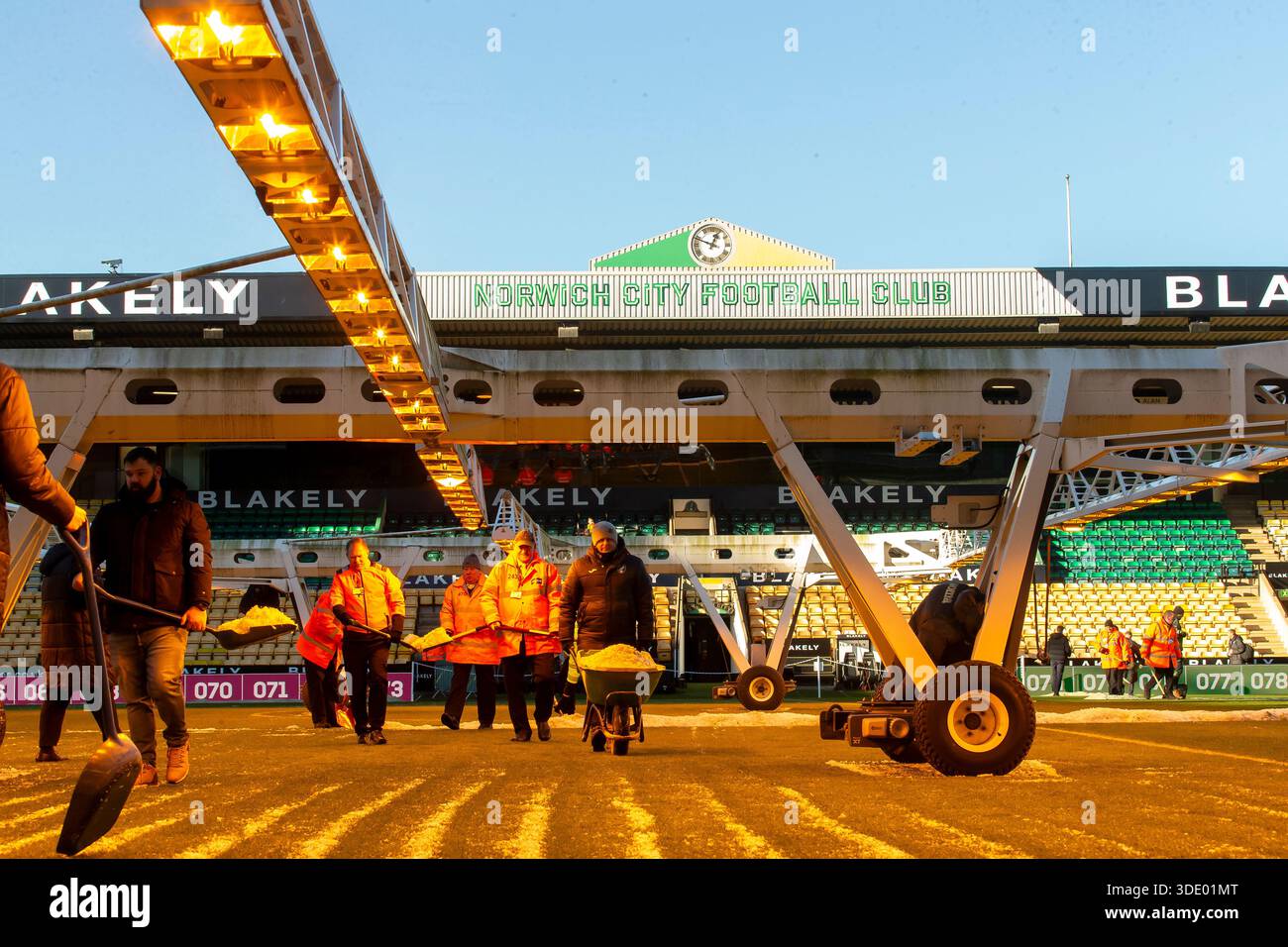 Norwich City stewards and staff clearing snow off the pitch before the ...