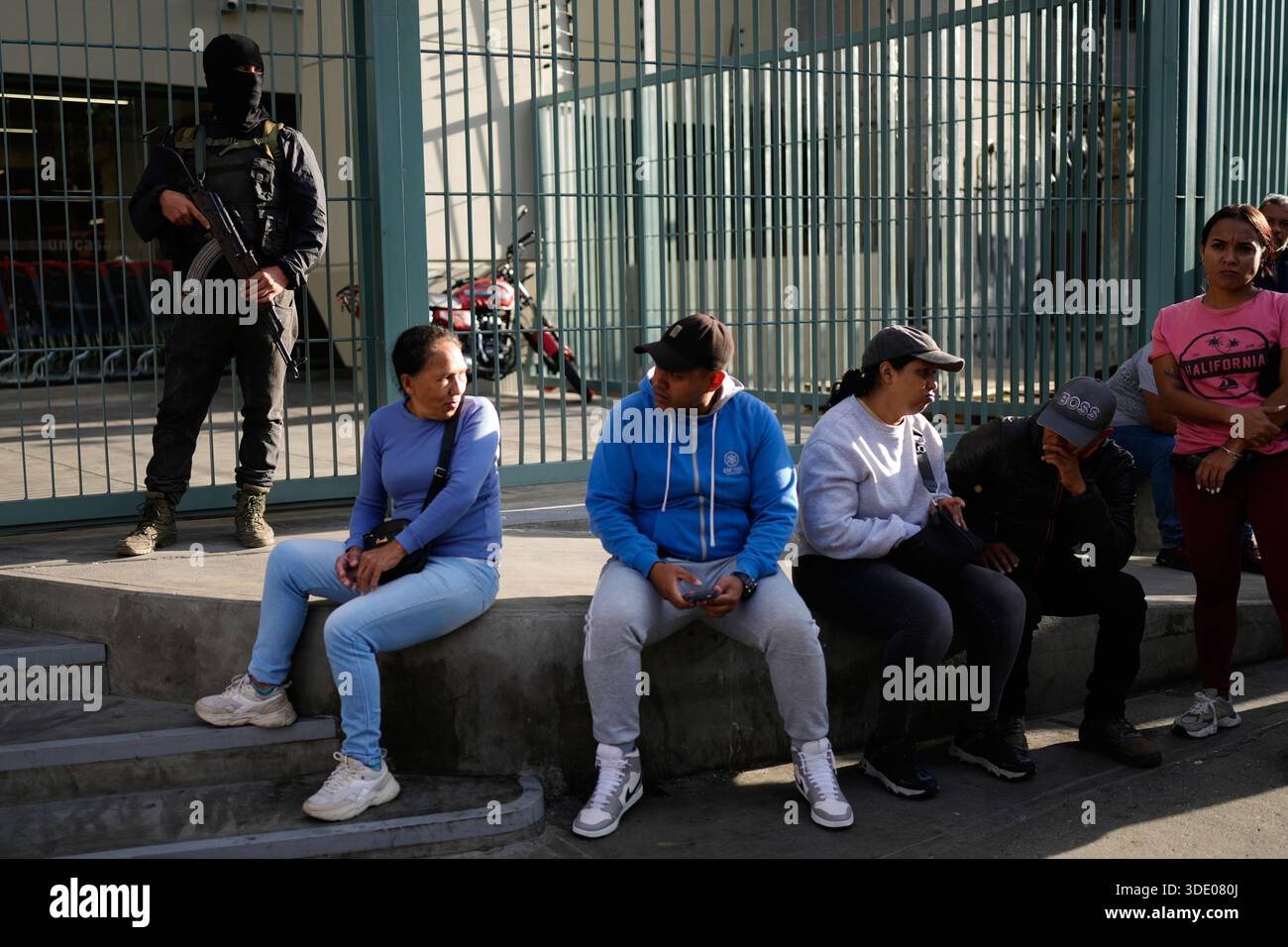 Shoppers line up outside a supermarket guarded by pro-government armed ...