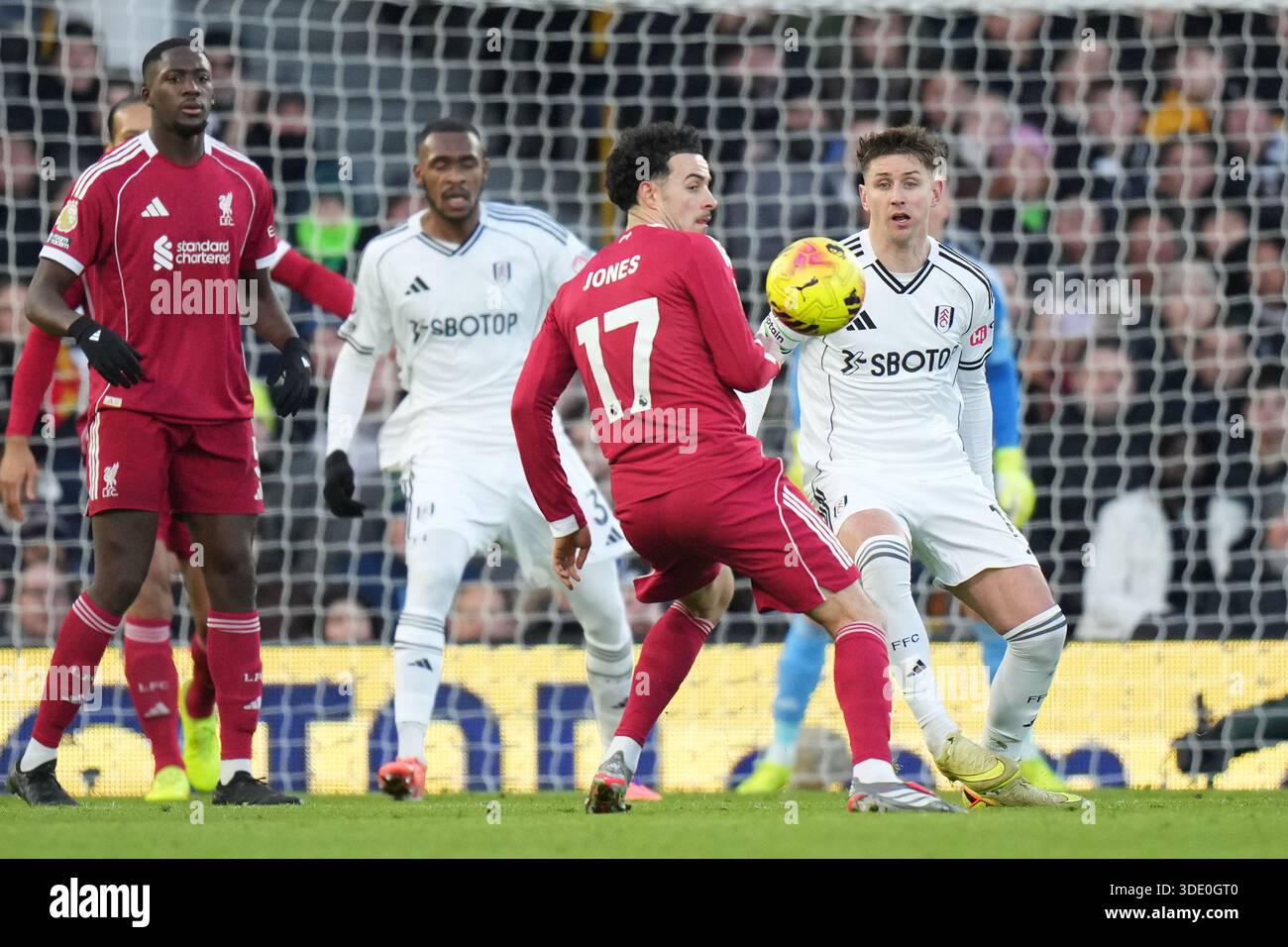 Liverpool's Curtis Jones challenges for the ball with Fulham's Tom ...