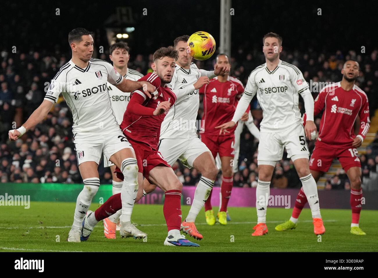 Fulham's Sasa Lukic clears the ball next to Liverpool's Conor Bradley ...