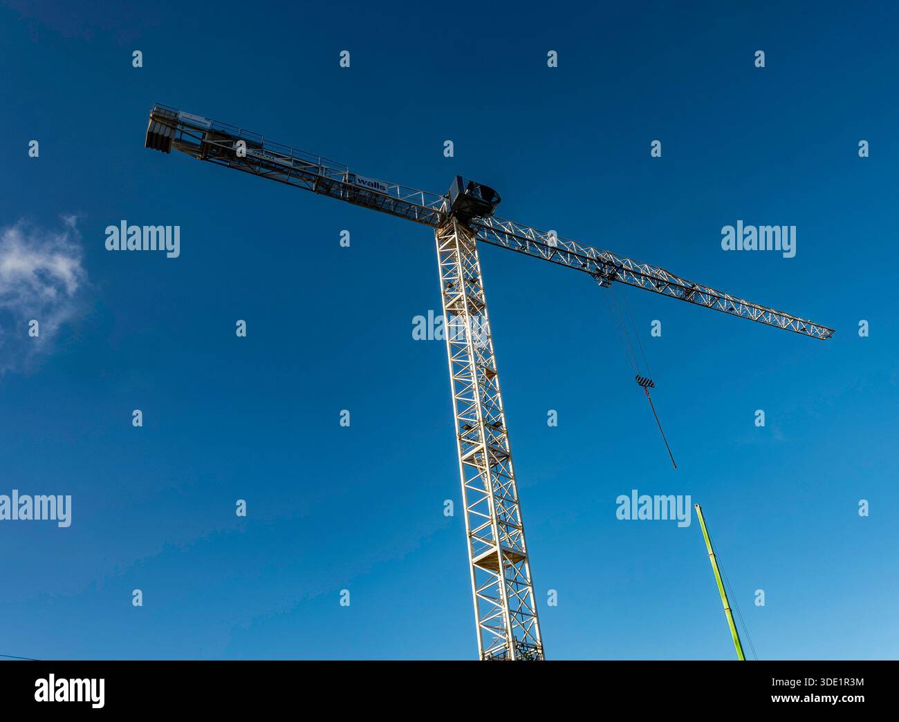A white tower crane by Walls Construction against a clear blue sky. A ...