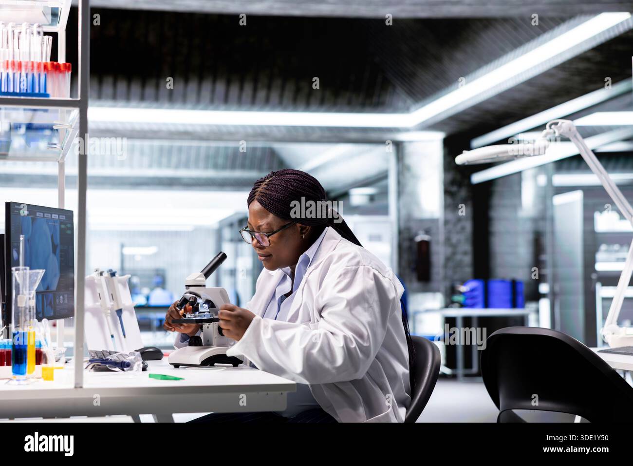 Researcher using microscope and specimen tray in laboratory workspace ...