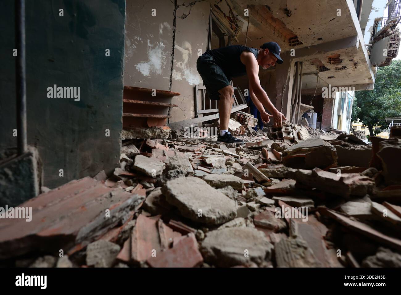 04 January 2026, Venezuela, La Guaira: A man collects debris from an ...
