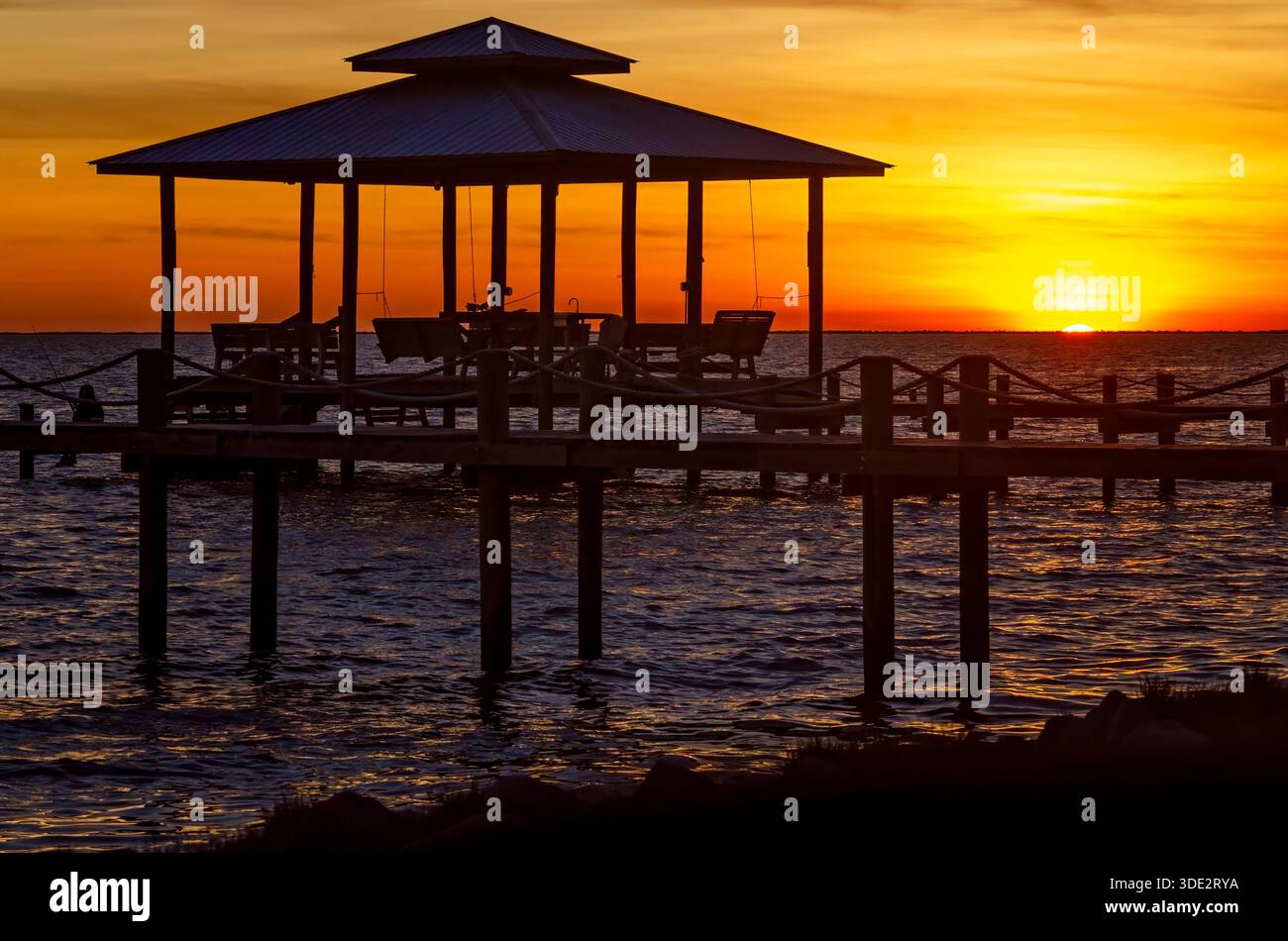 A fishing pier is silhouetted by the setting sun on Coden Beach, Jan. 1 ...