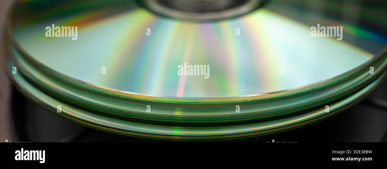 A set of shiny compact discs sits on a black holder. The discs reflect ...