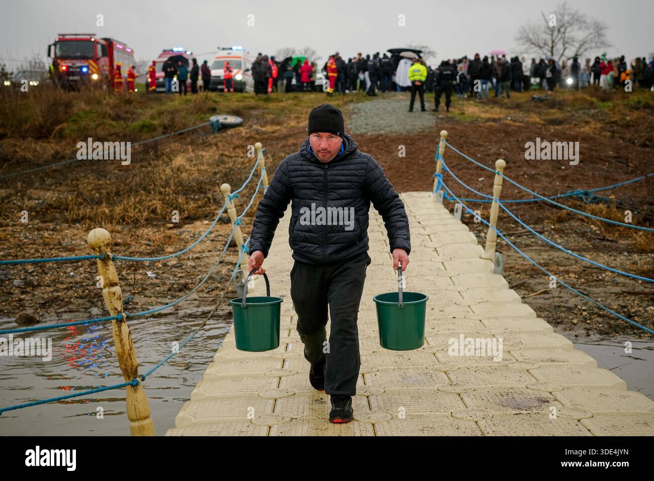 A man carries buckets of water on a bank of the river Danube before a ...