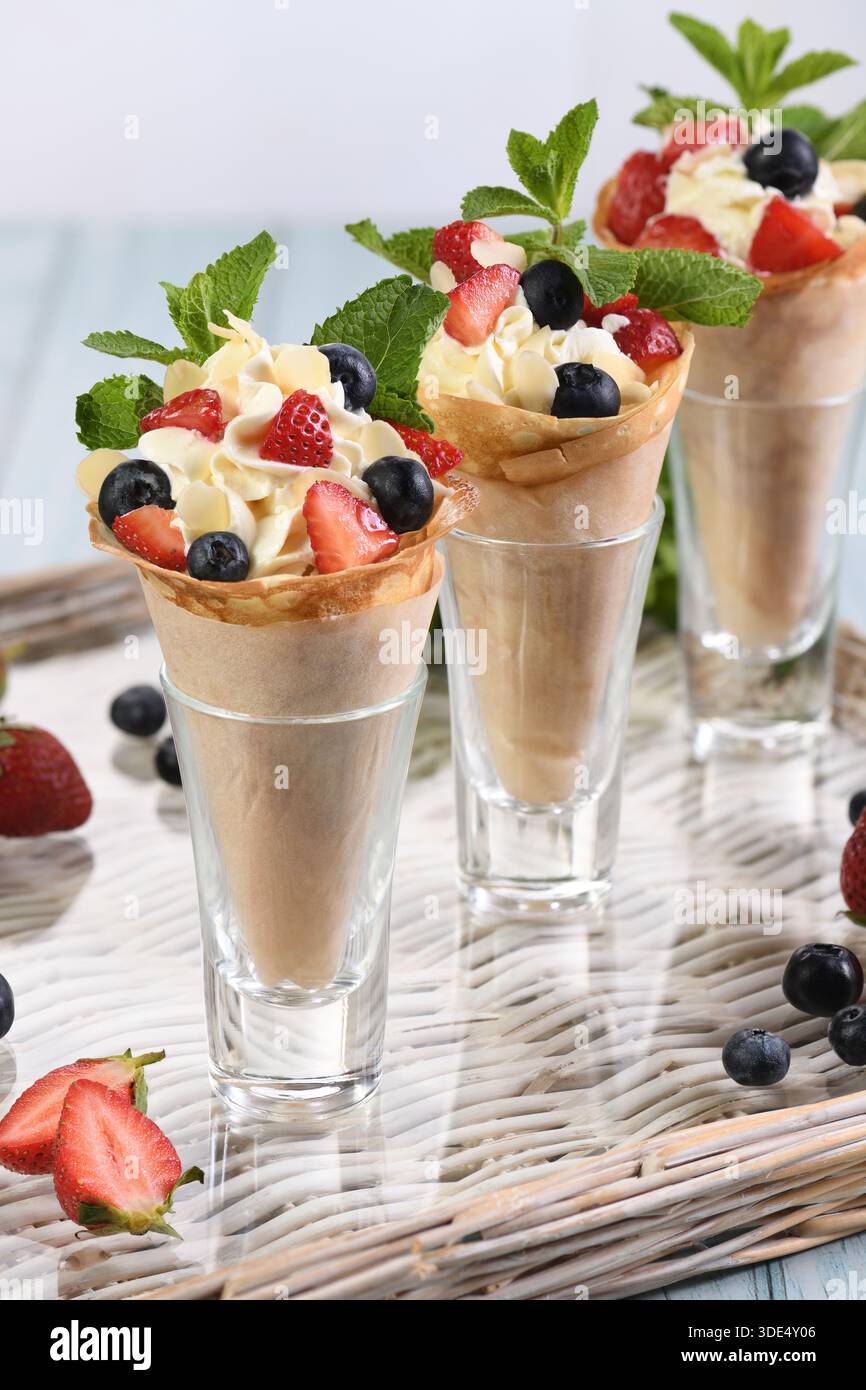 Crispy crepe cones filled with whipped cream, strawberries, blueberries ...