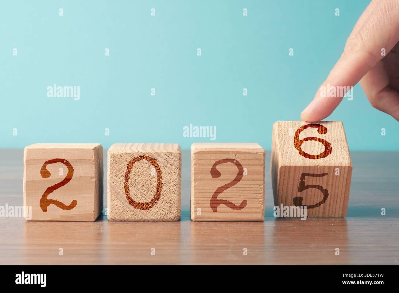 A businessman turns a wooden cube from 2025 to 2026, New Years concept ...