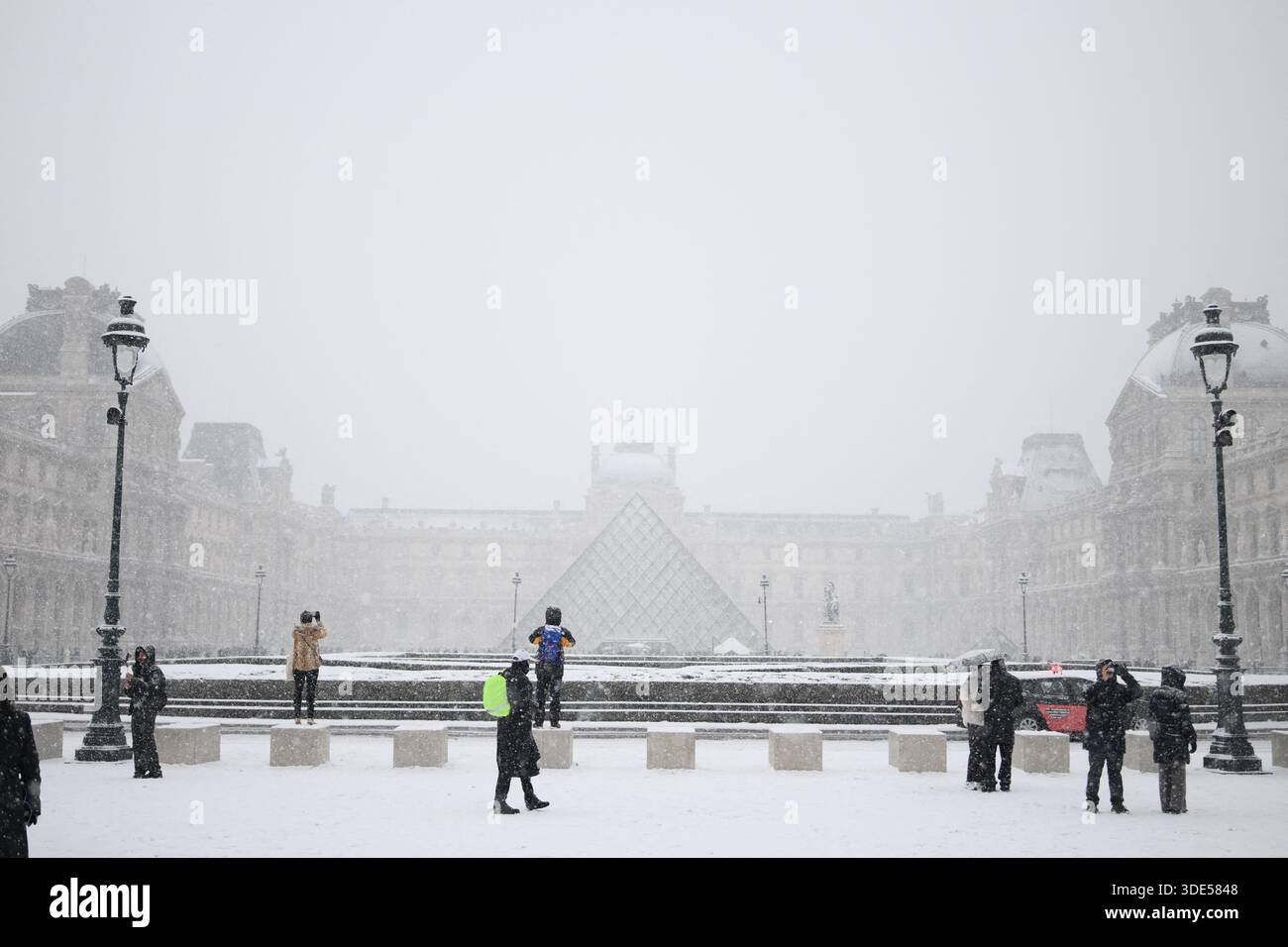 Tourists in front of the Louvre museum under the snow during a cold ...