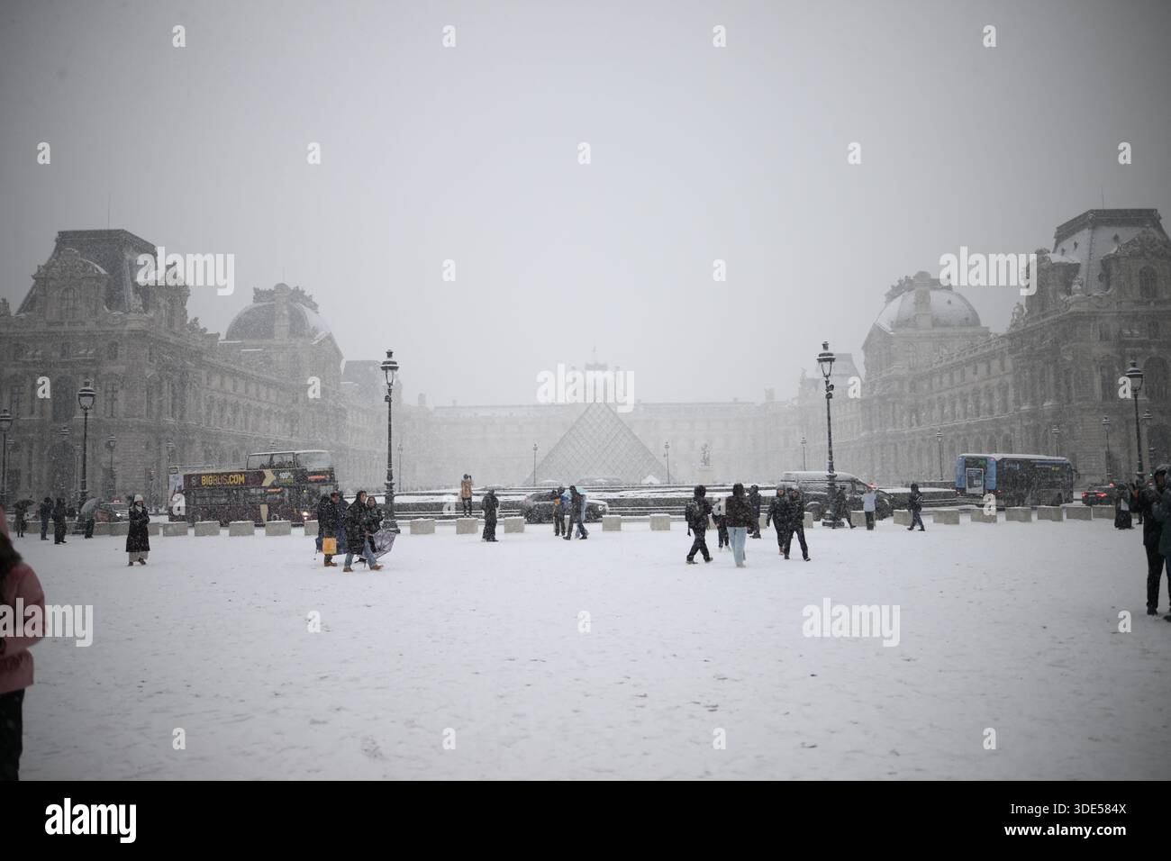 Tourists in front of the Louvre museum under the snow during a cold ...