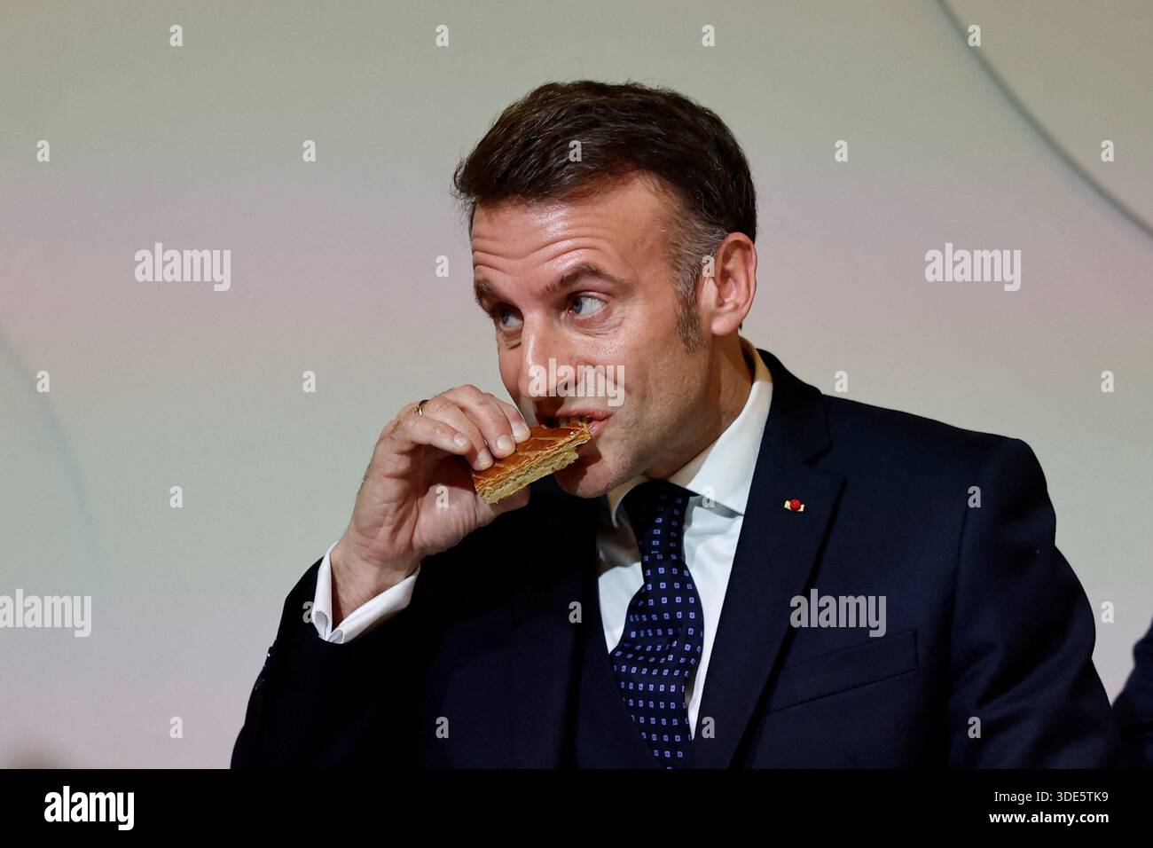 French President Emmanuel Macron eats a piece of the traditional ...