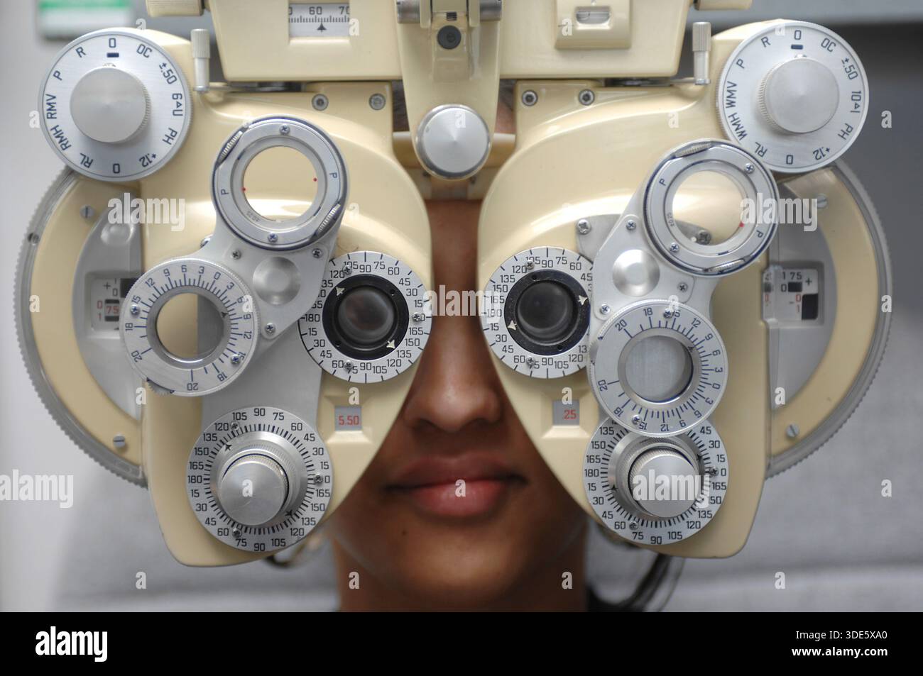 A woman undergoing examination with a Ophthalmic Phoropter Machine ...