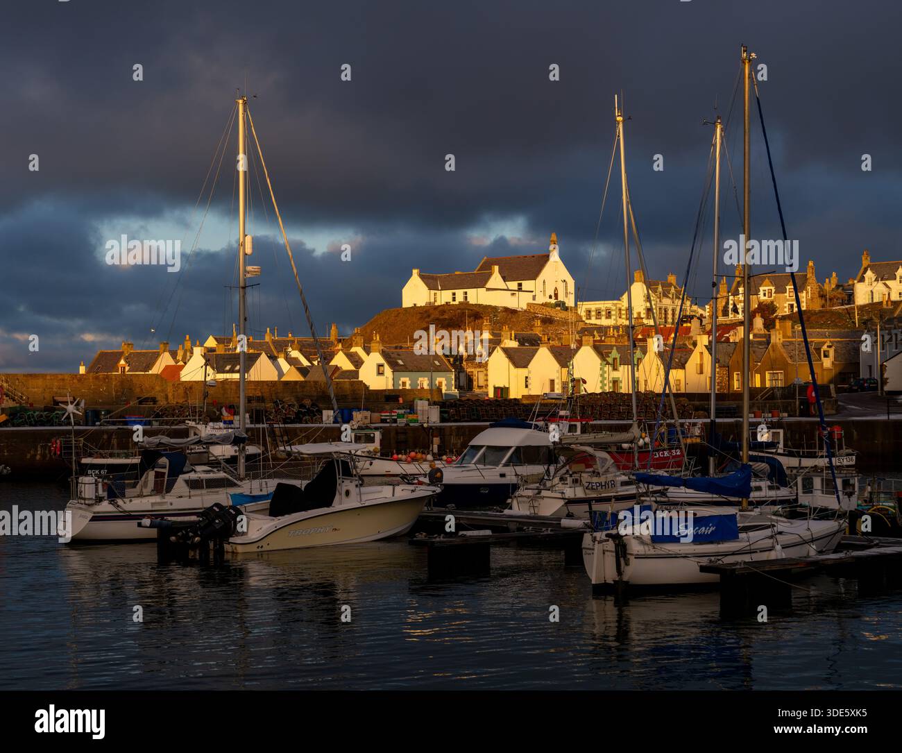 Golden rays of the sun touch the Harbour area in Findochty while dark ...