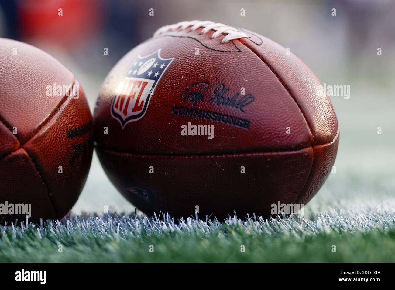 Footballs with the NFL shield logo rest on the field during warm-ups ...