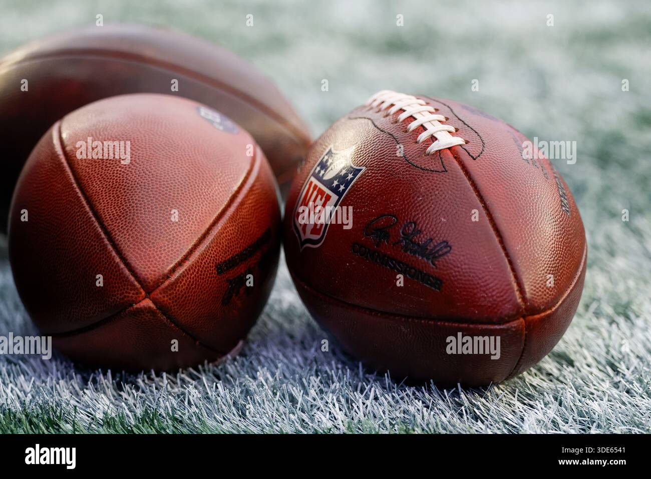 Footballs with the NFL shield logo rest on the field during warm-ups ...